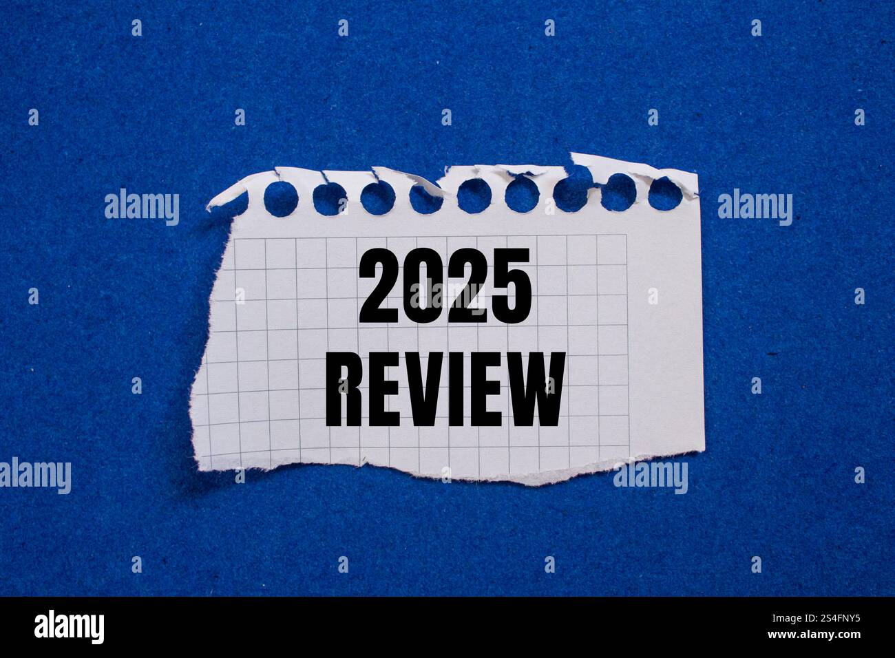 2025 review message written on ripped torn paper piece with blue background. Conceptual 2025 ...
