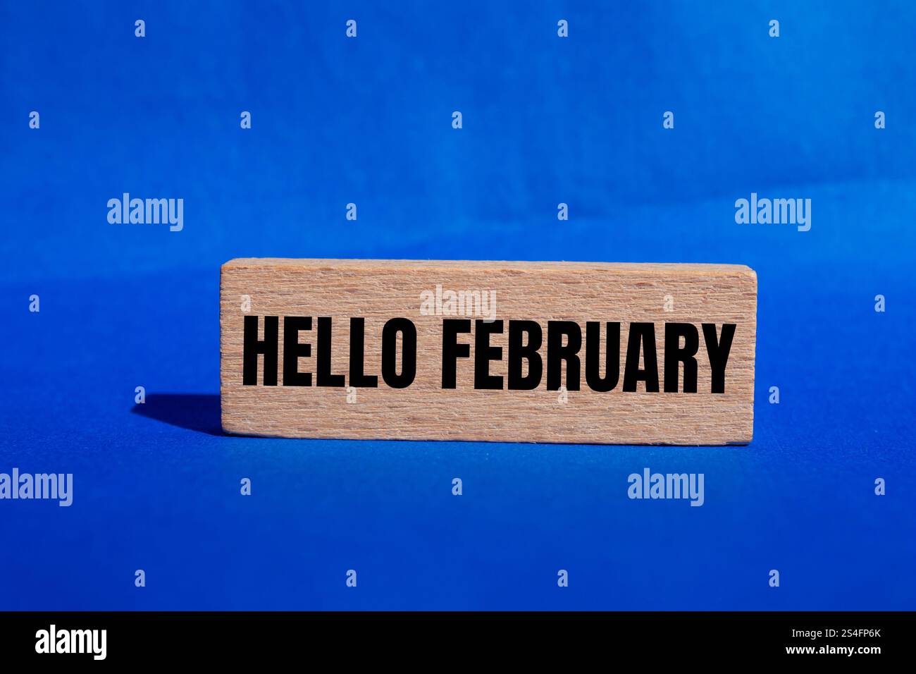 Hello february message written on wooden block with blue background ...