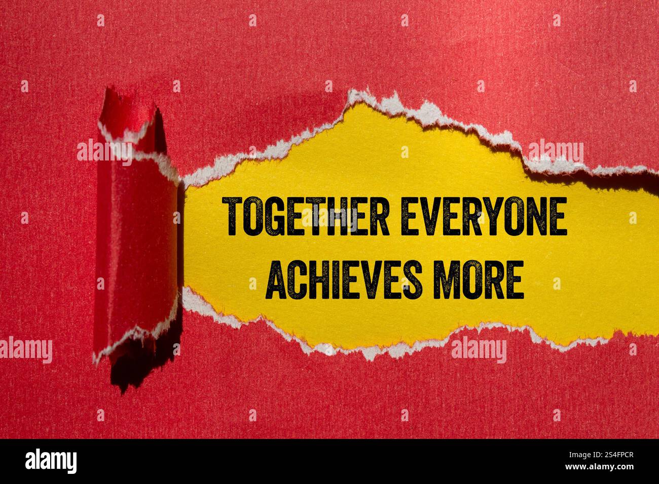 Together everyone achieves more message written on ripped torn red paper on yellow background ...