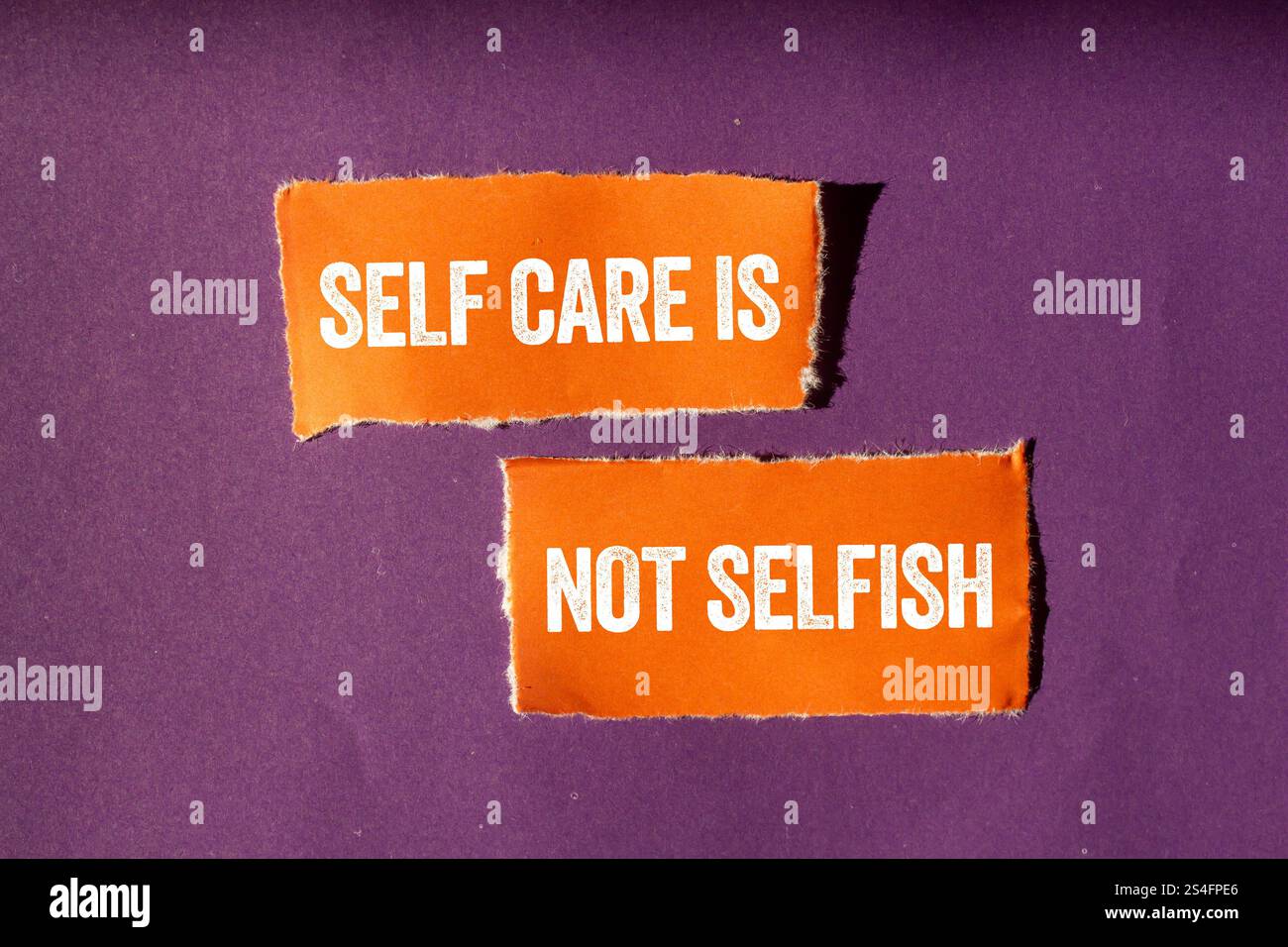 Self care is not selfish message written on ripped torn orange paper pieces on purple background ...