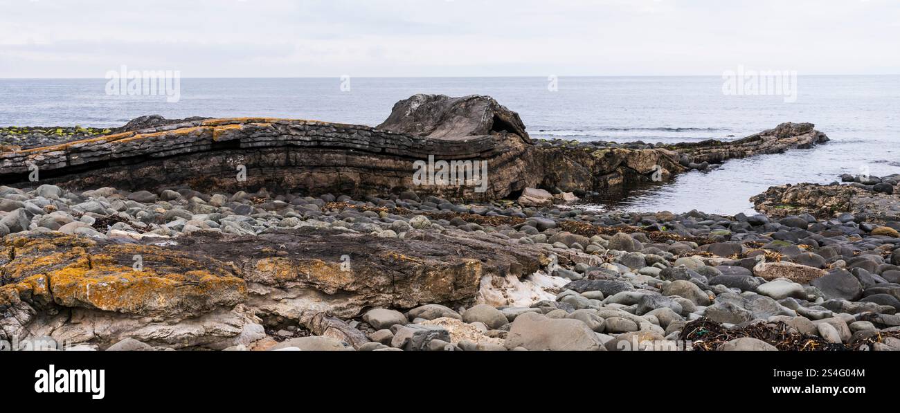 Dunstanburgh bay Northumberland. Exposed rocks reveal volcanic origins ...