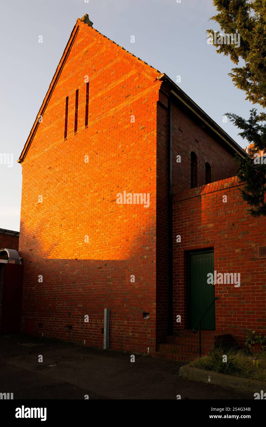 Rear of a red brick church building illuminated by the setting sun ...