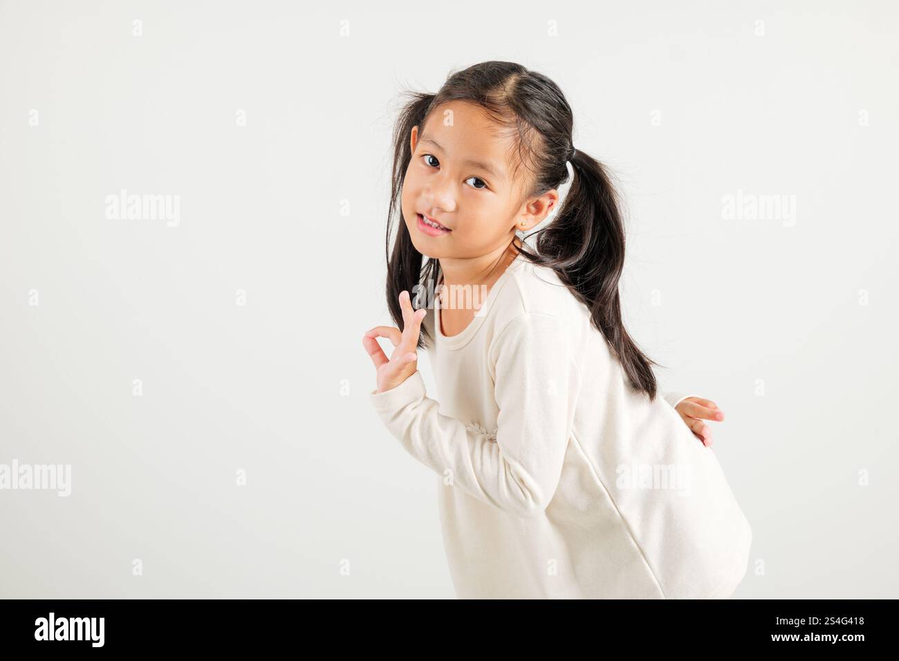 Exuberant young kid girl showcases the OK sign with an optimistic smile ...