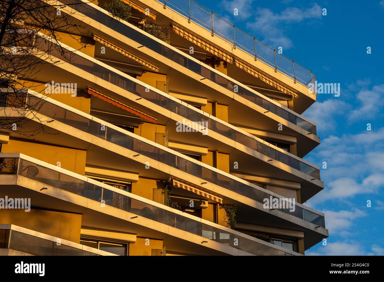 Modern residential building reflects evening sunlight under a clear sky ...