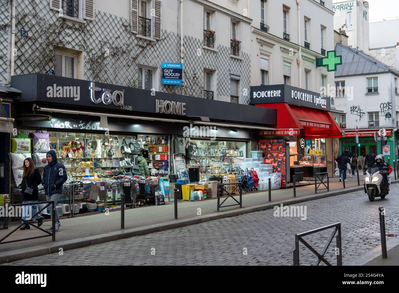 Shops line a busy street in a vibrant Paris neighborhood during late ...