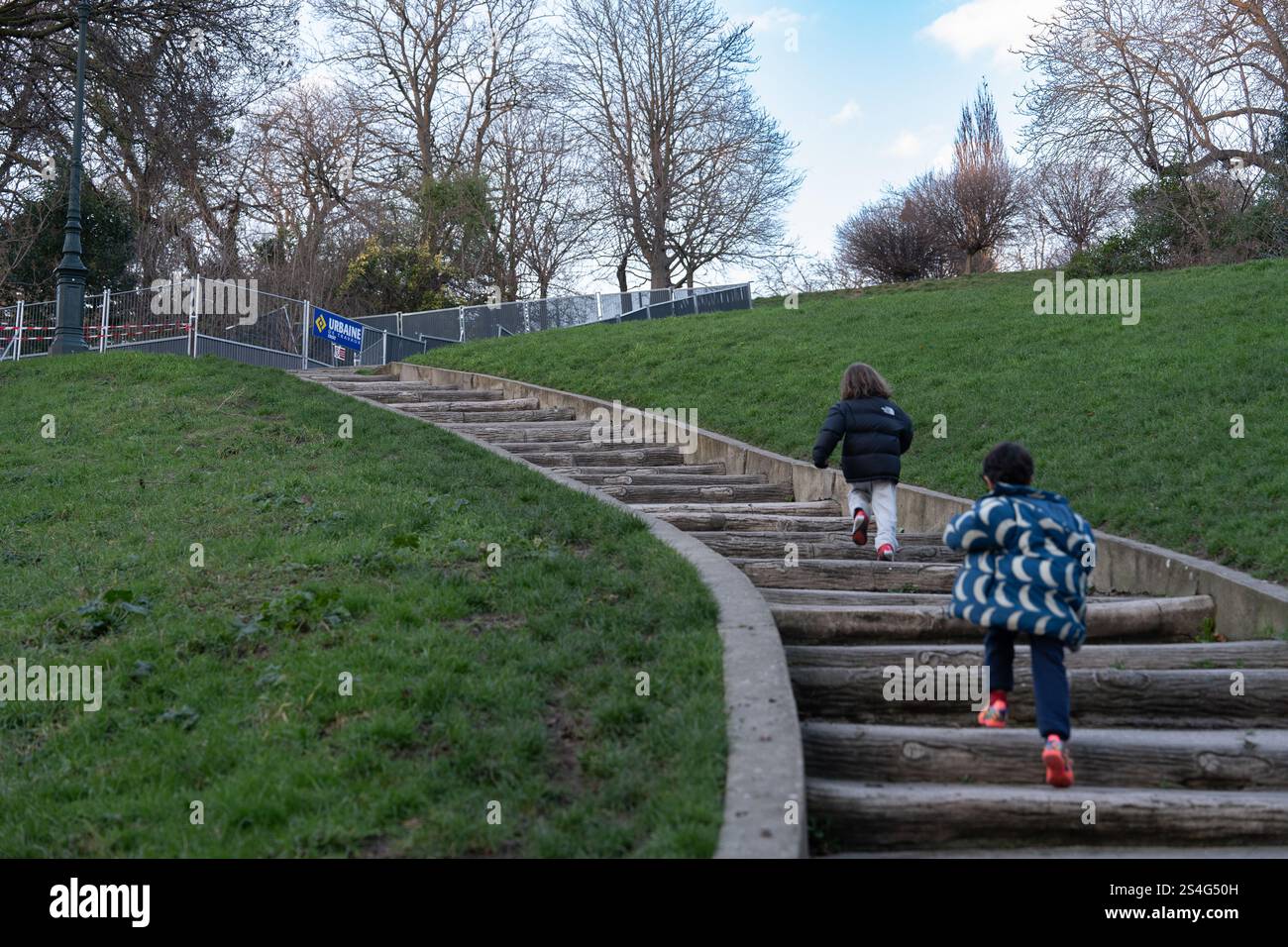 Children playfully running up wooden steps in a grassy park area Stock ...