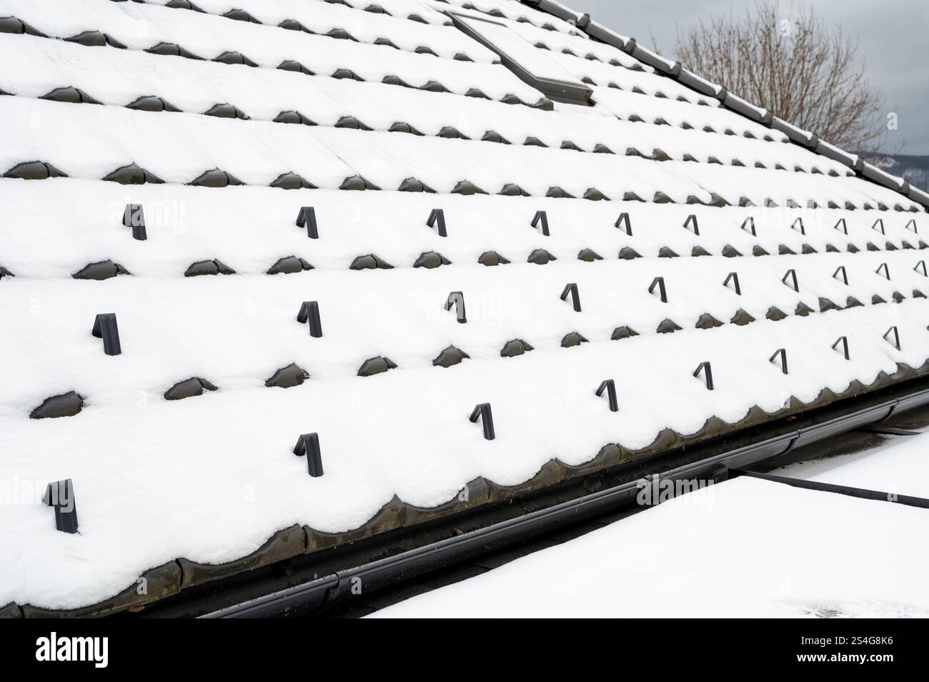 Snow guards, retainers or snow hooks on the tile roof covered by snow ...