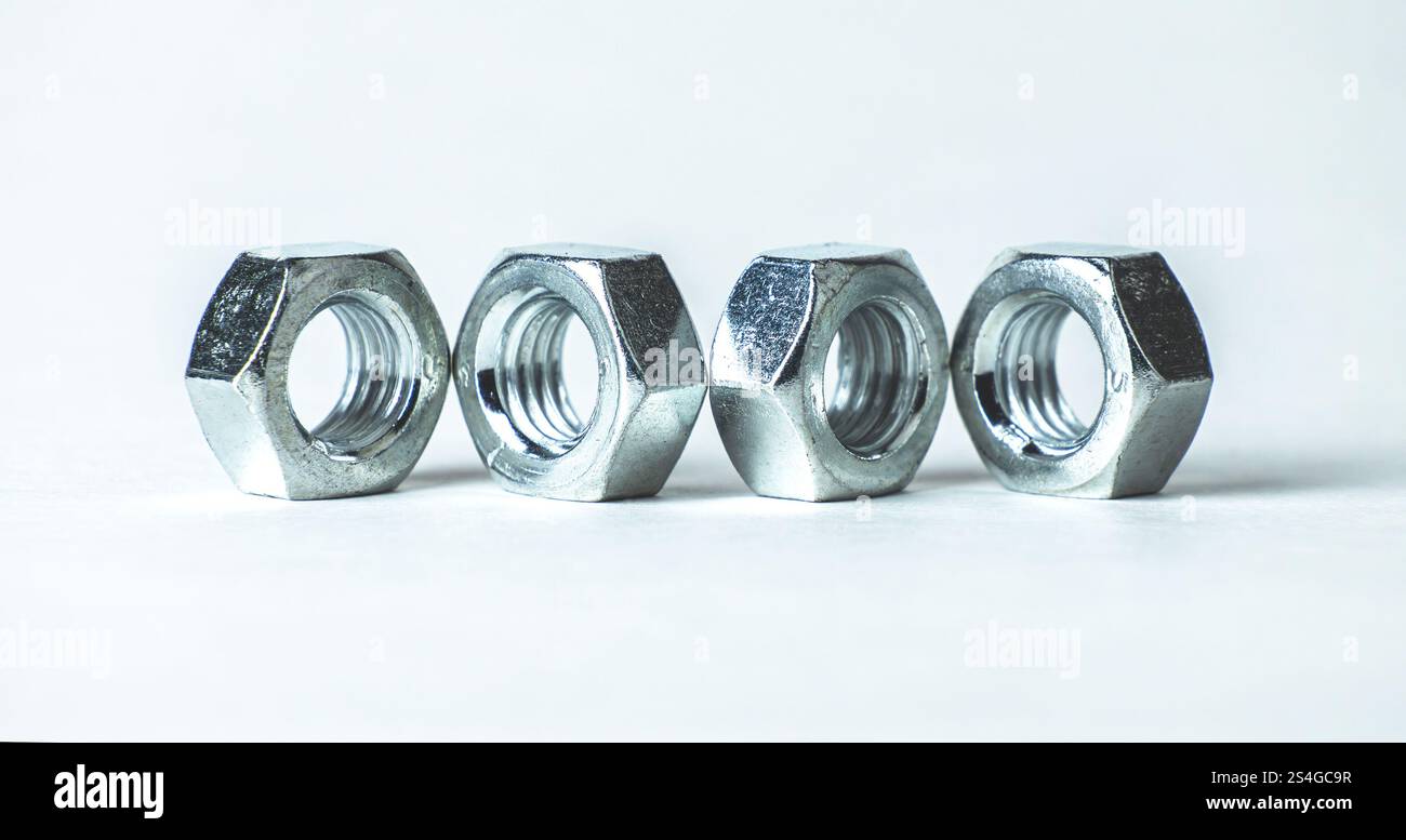 Four metallic nuts placed in a straight line showcasing their hexagonal ...