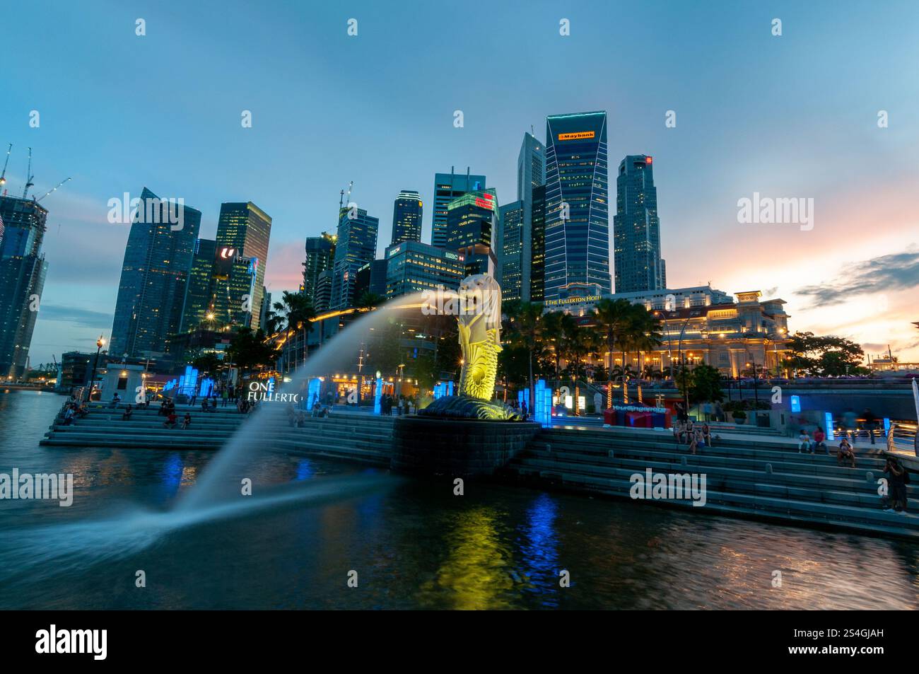 Dusk over the financial district and the symbol of Singapore, the ...
