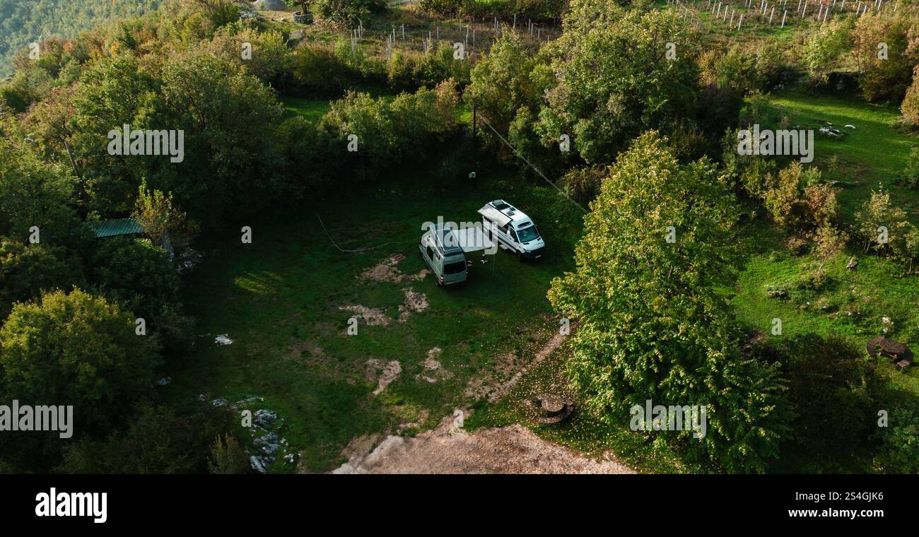 Two large camper vans - mobile homes are parked at a camping site in a ...