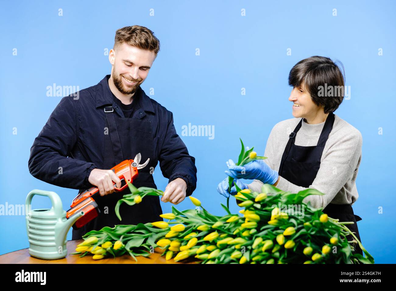 Flower shop. A young guy helps an older woman florist take care of ...