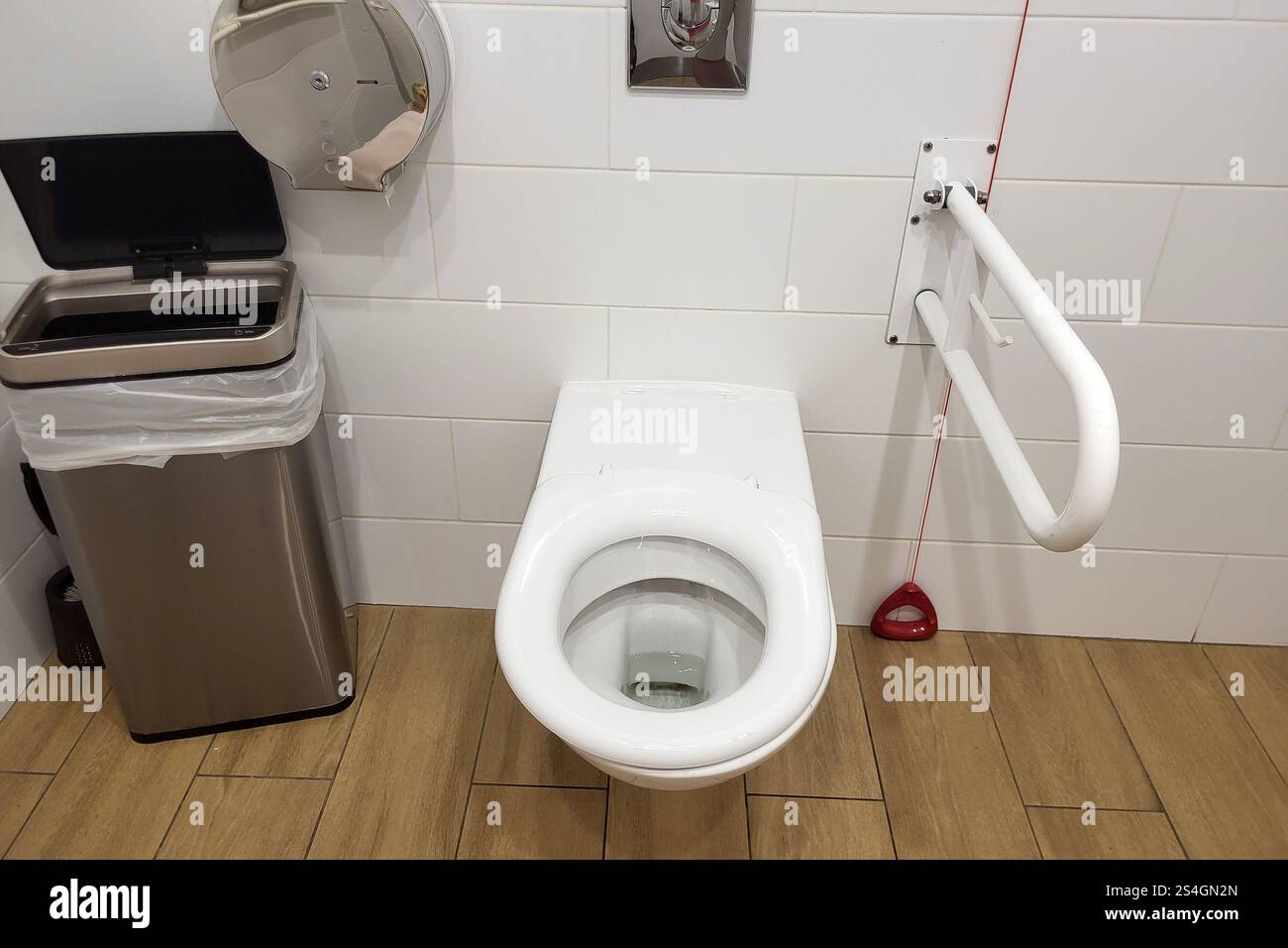 Public restroom with toilet, safety grab bar, trash bin, and emergency ...