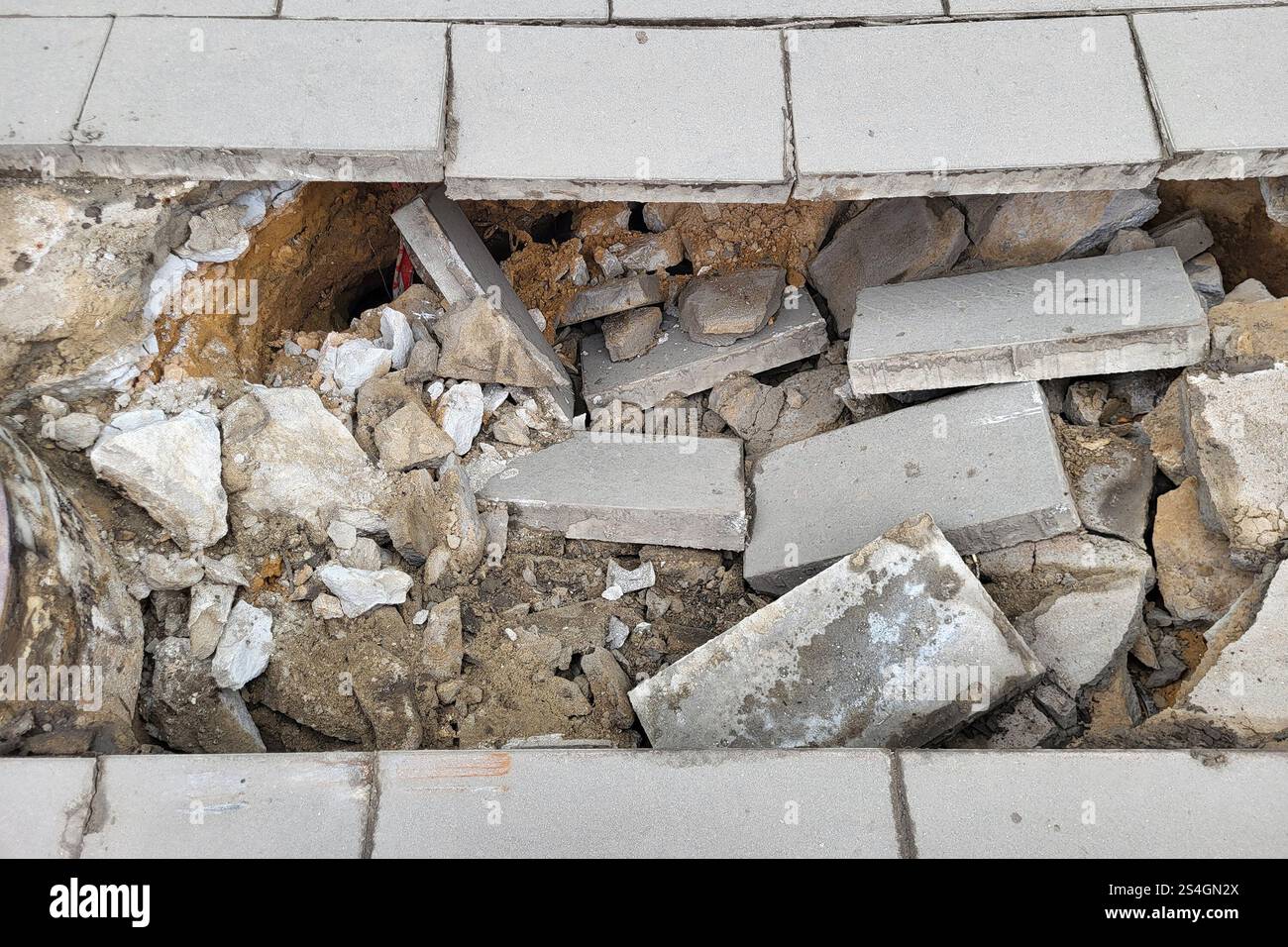 Broken pavement tiles and debris with exposed ground underneath ...