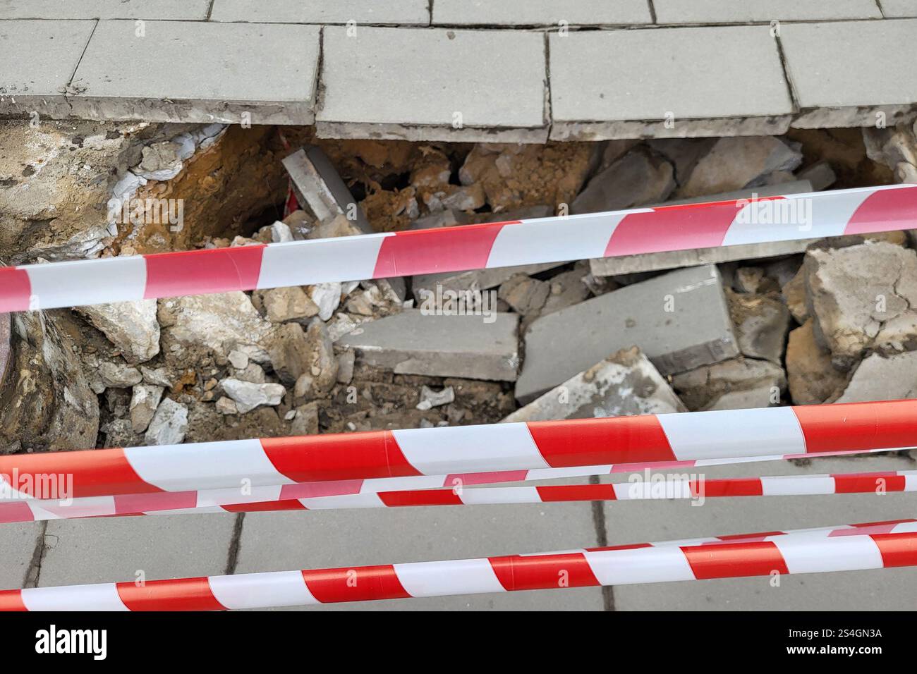 Collapsed sidewalk with red and white safety tape. Construction site ...