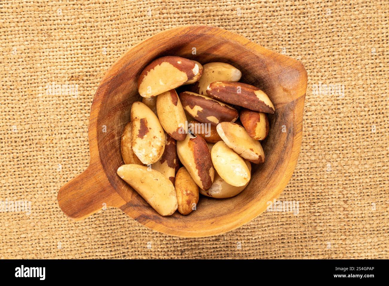 Brazil nuts without shells with wooden cup on jute cloth, close-up, top ...