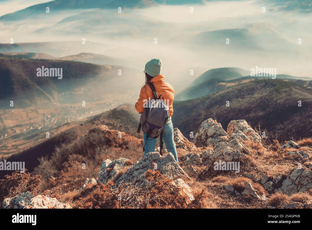 Cheering woman backpacker enjoy the view on sunrise mountain top cliff ...