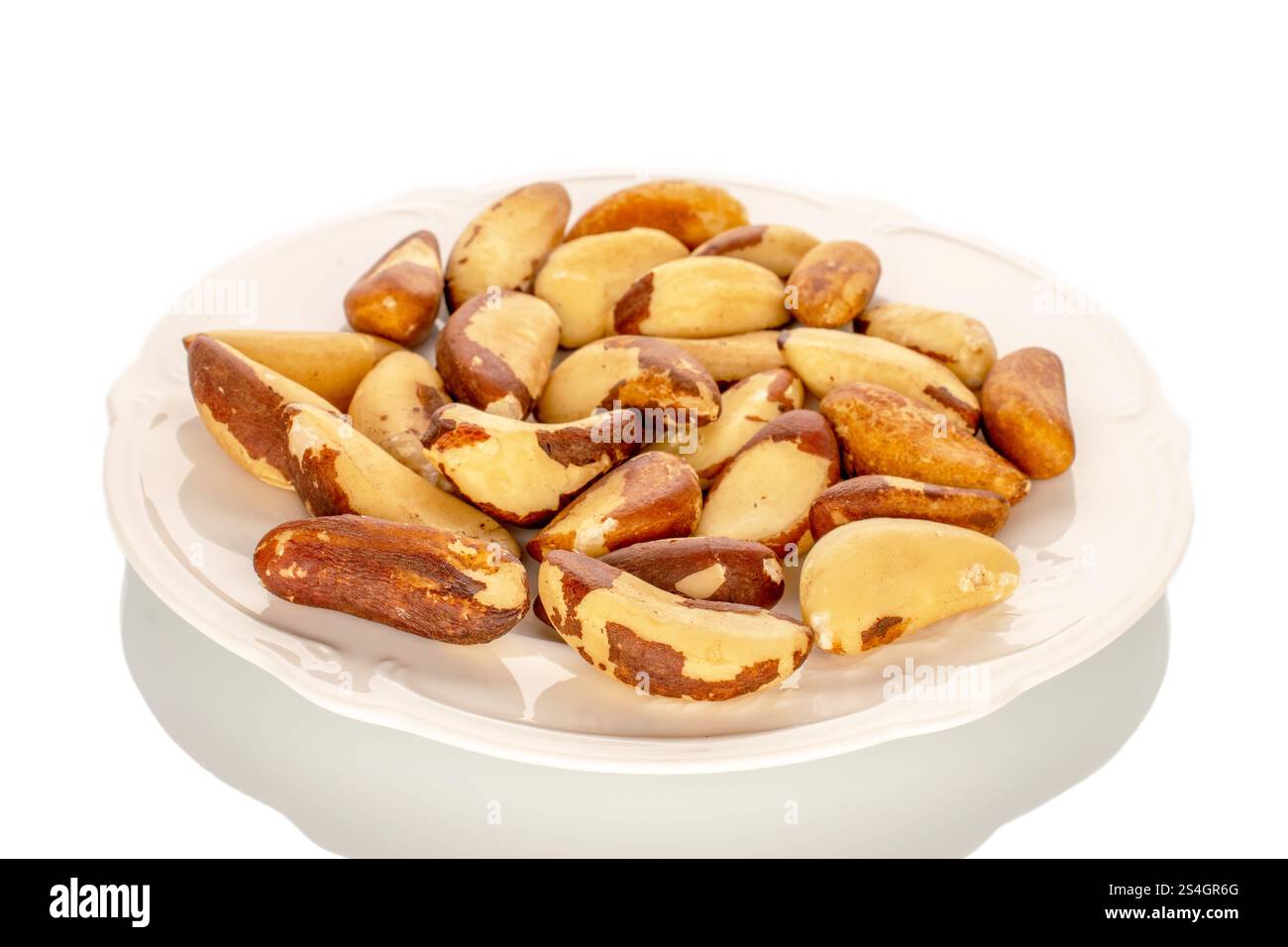 Brazil nuts without shells on a white ceramic plate, close-up, isolated ...