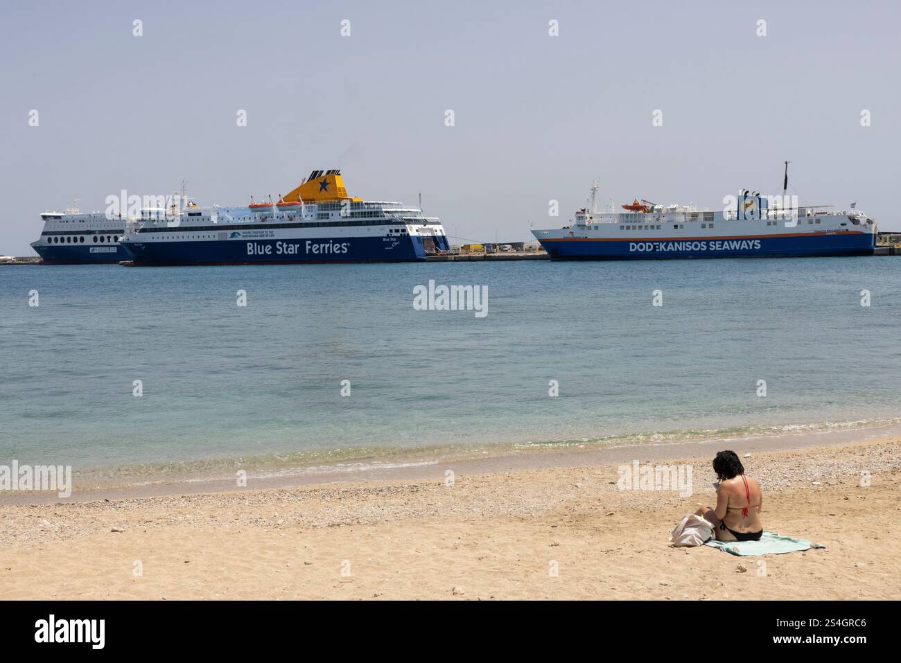 A woman sunbathes on the harbour beach, Rhodes Town, main town on ...