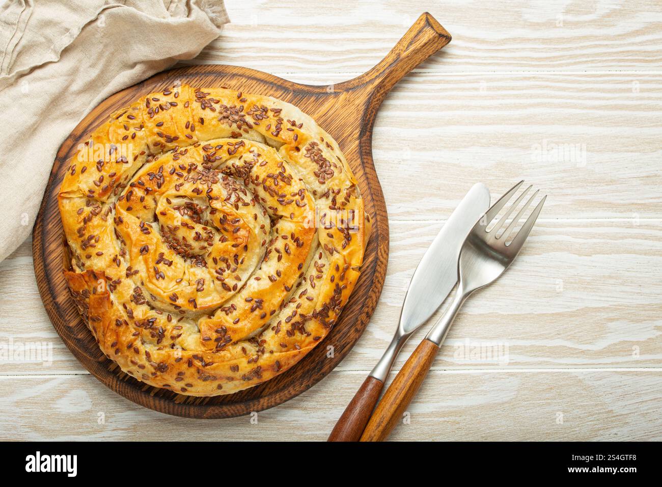 Burek made of filo dough with filling on cutting board, white wooden ...