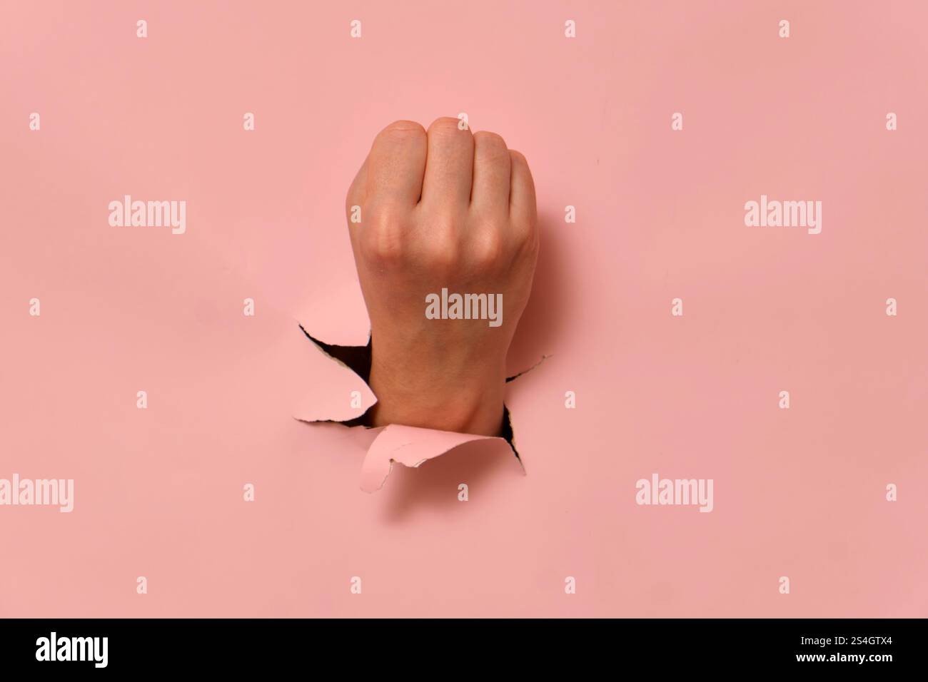 Hand breaking through pink paper wall with clenched fist. Conceptual ...