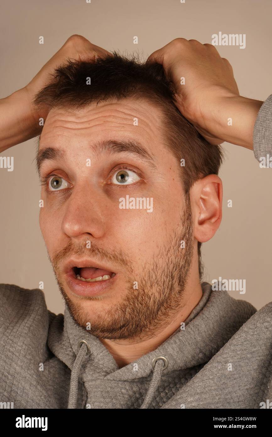 A man with his hands on his hair, a common gesture, is experiencing ...