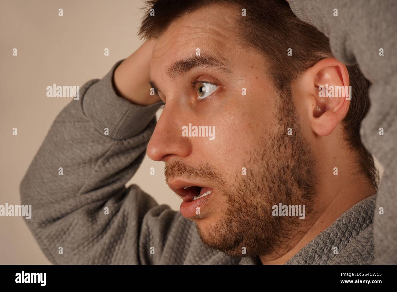 With both hands placed firmly on his head, the man shows signs of ...