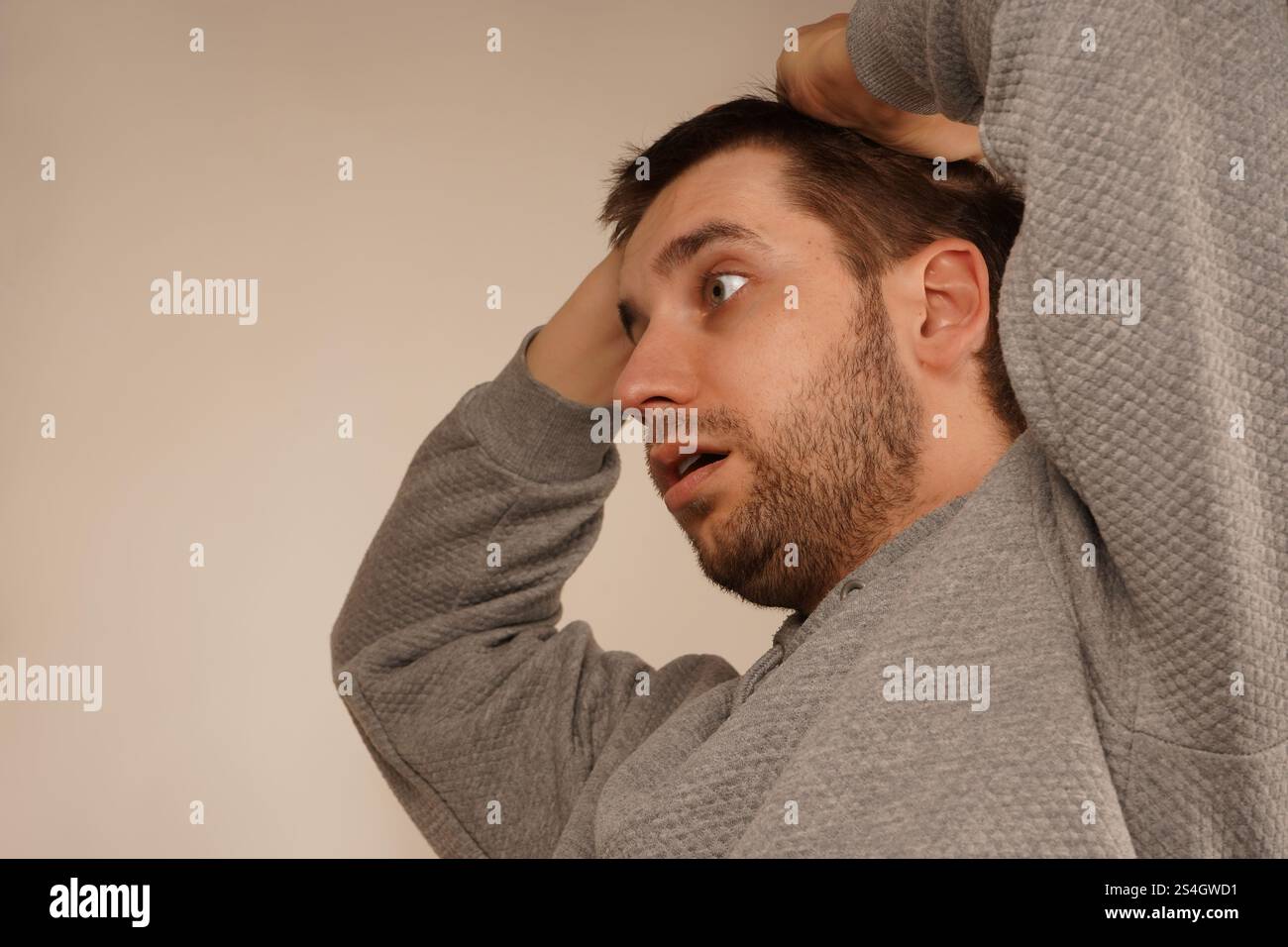 With both hands placed firmly on his head, the man shows signs of ...