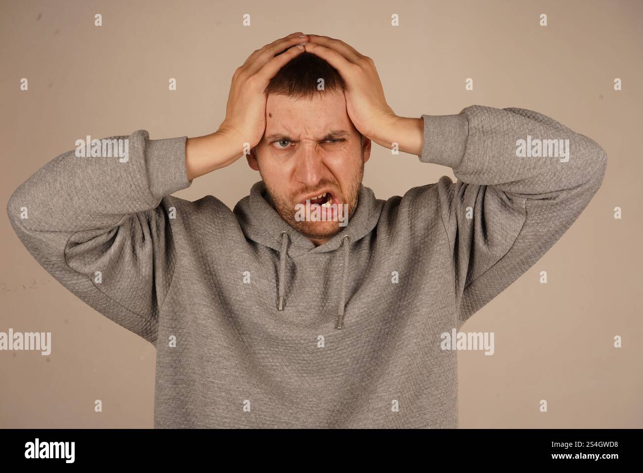 With both hands placed firmly on his head, the man shows signs of ...