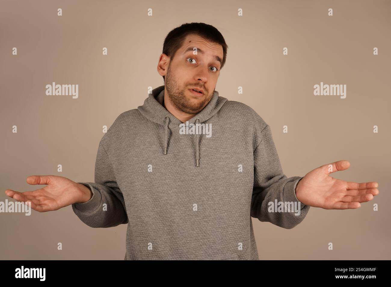 With hands extended outward, a man shrugs, appearing confused. The open ...