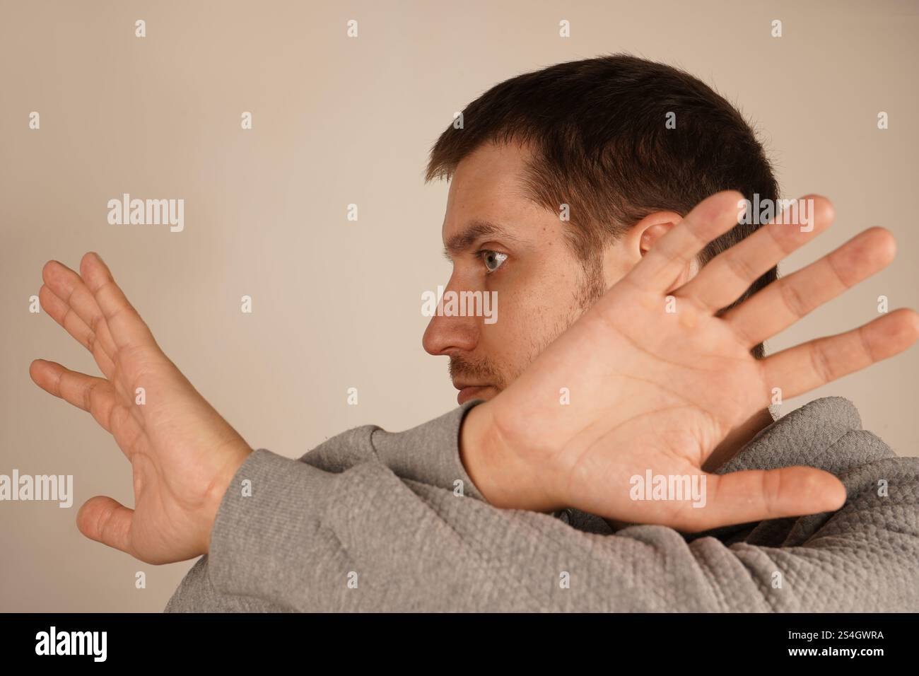 With arms crossed and fingers spread wide, a man creates a gesture of ...