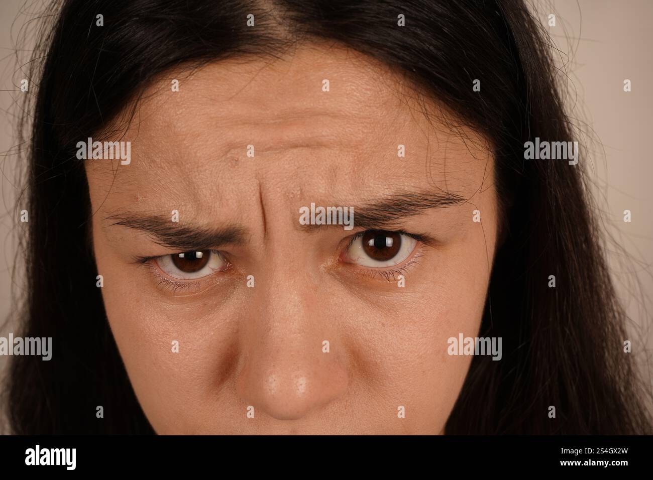 A young woman with furrowed brows displays an expression of seriousness ...