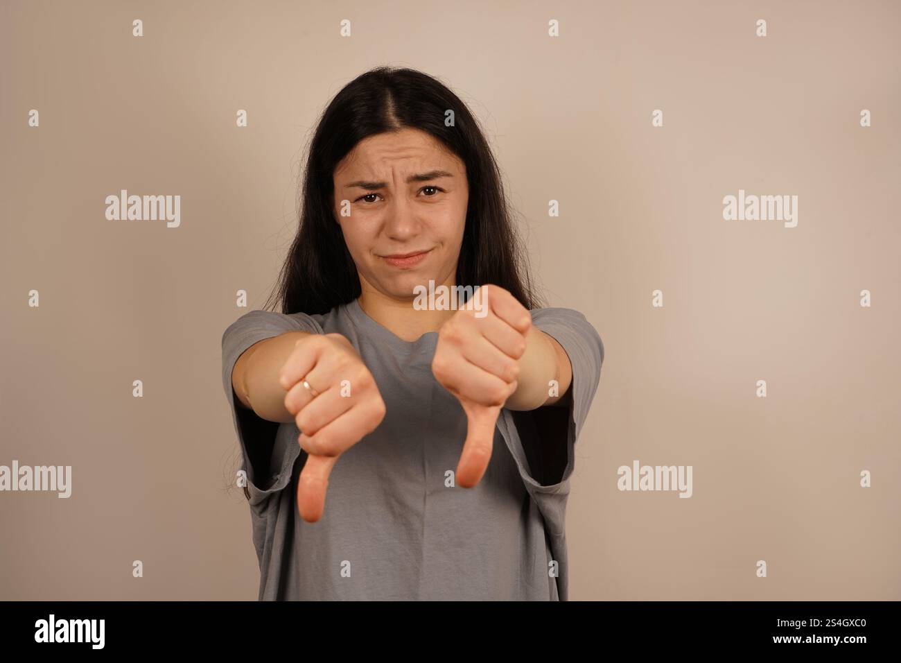 Serious woman showing double thumbs down gesture, expressing ...