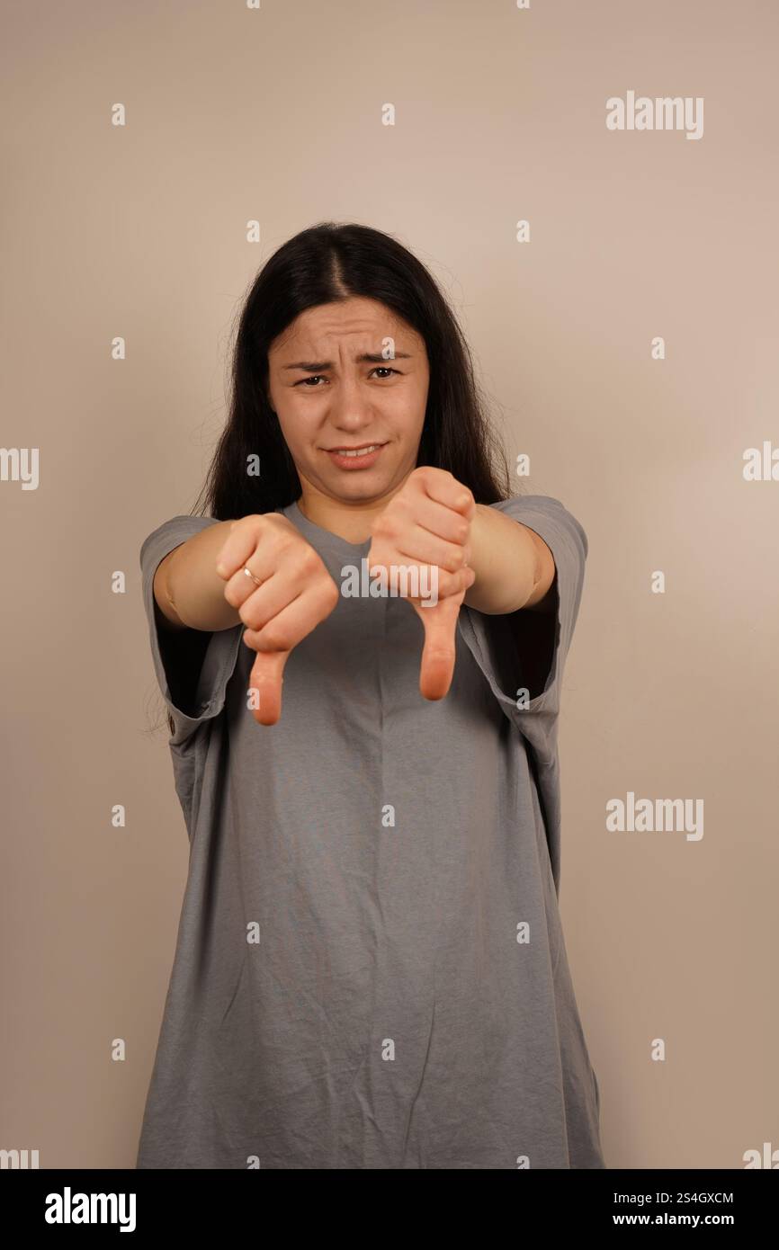 Serious woman showing double thumbs down gesture, expressing ...