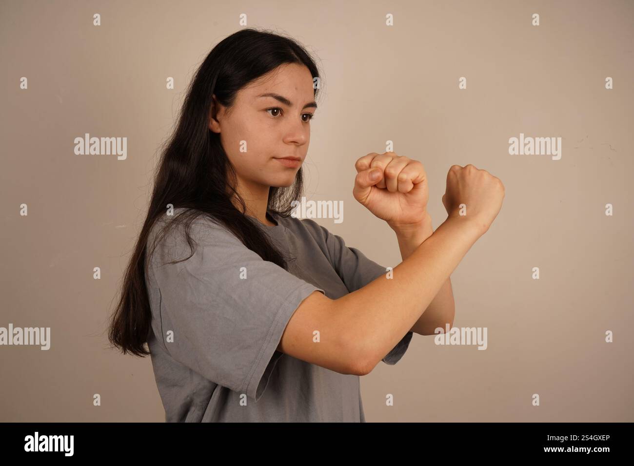 Her posture conveys a sense of defense and strength. The gesture shows ...