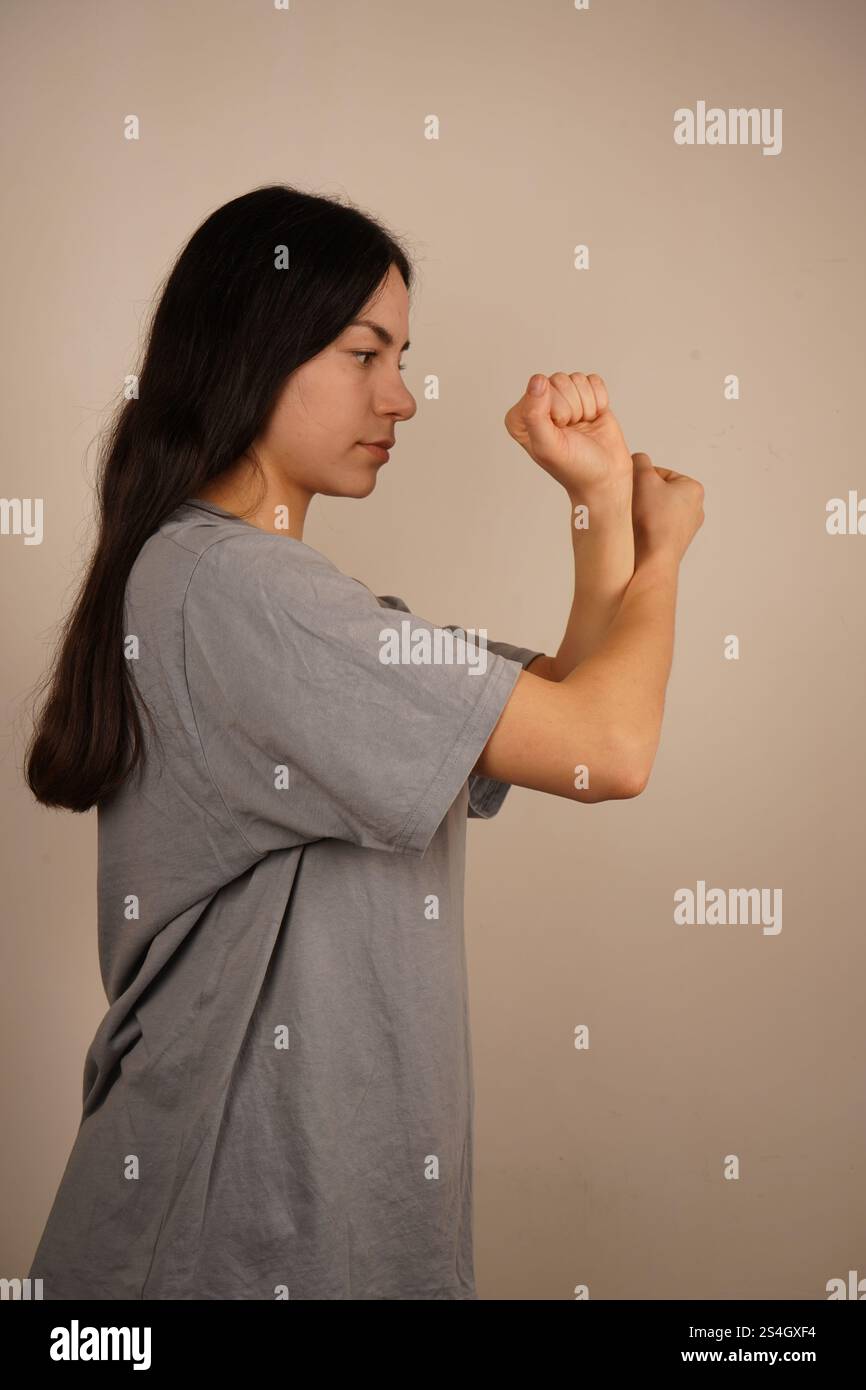 A woman crosses her arms in front of her, fists clenched, signaling ...