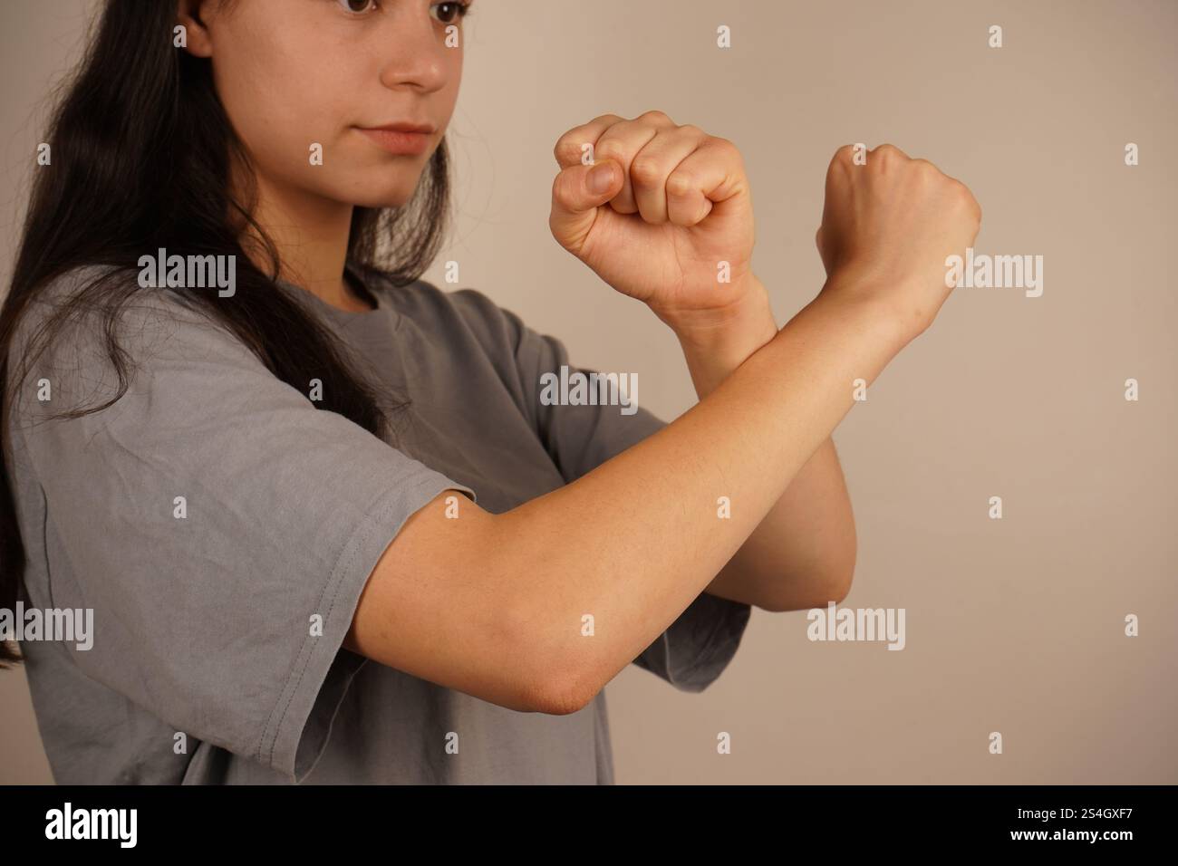 A woman crosses her arms in front of her, fists clenched, signaling ...