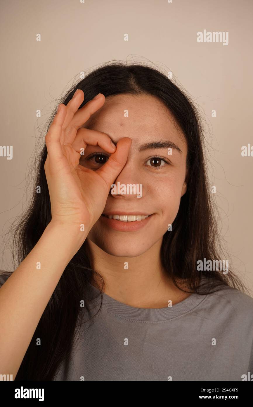 A woman playfully makes an "OK" sign near her eye, adding to the moment ...