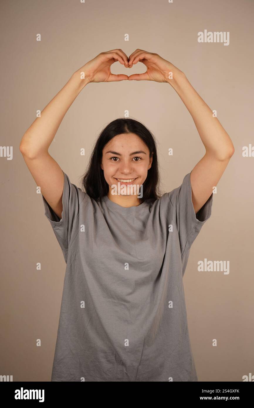 The young woman forms a heart shape with her hands, radiating warmth ...