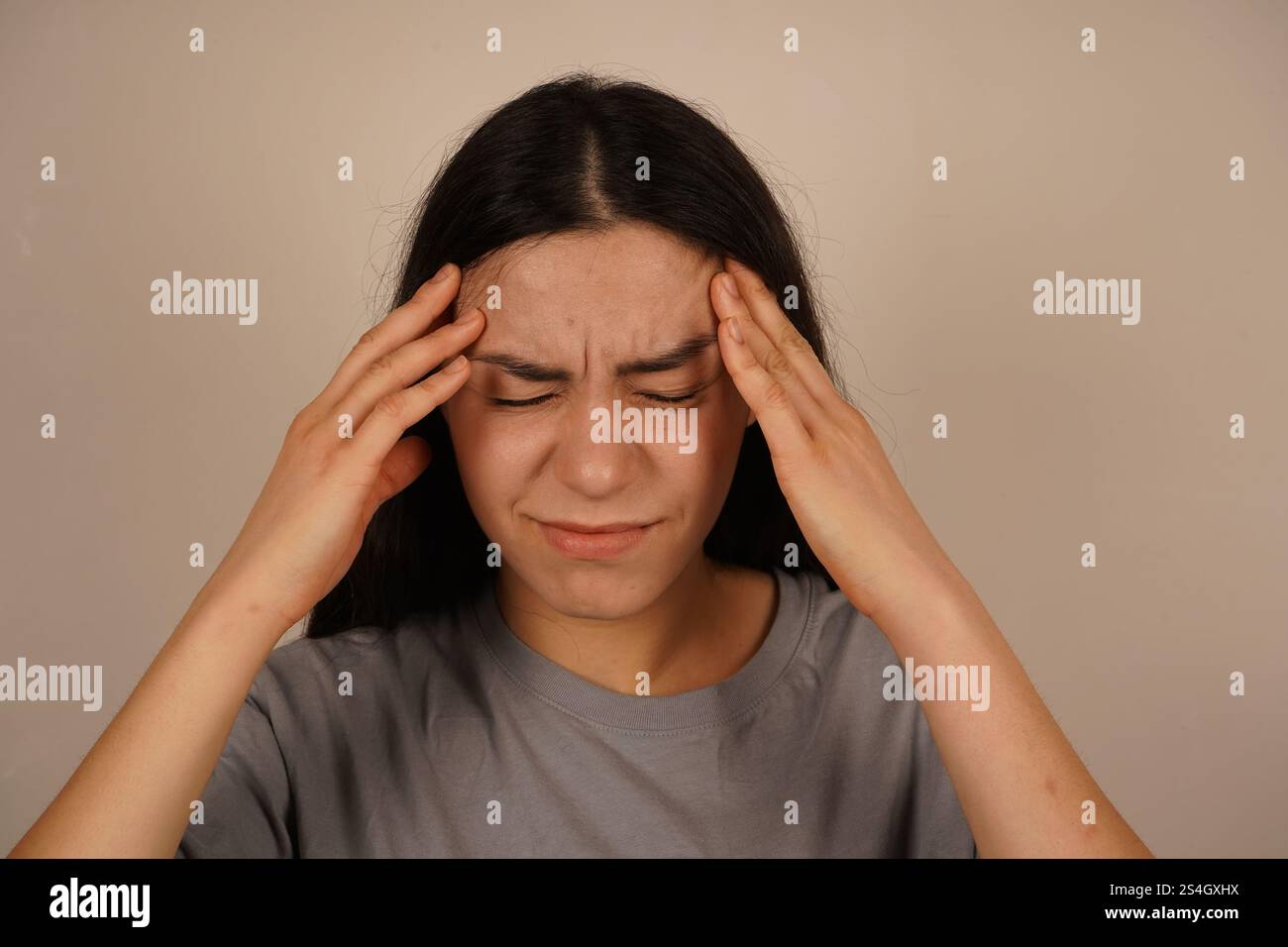 The woman touches her temple with one hand, signaling the agony of a ...