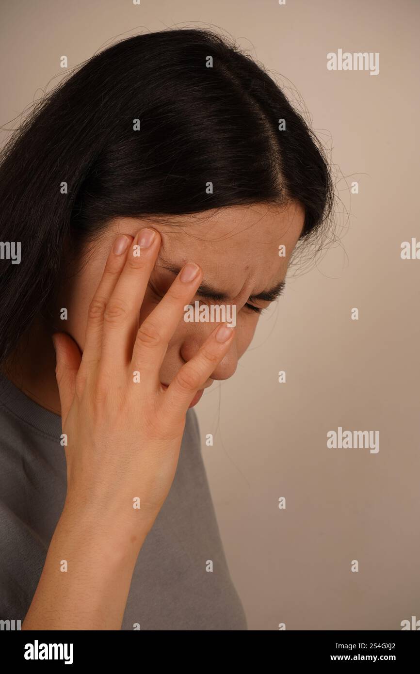 The woman touches her temple with one hand, signaling the agony of a ...