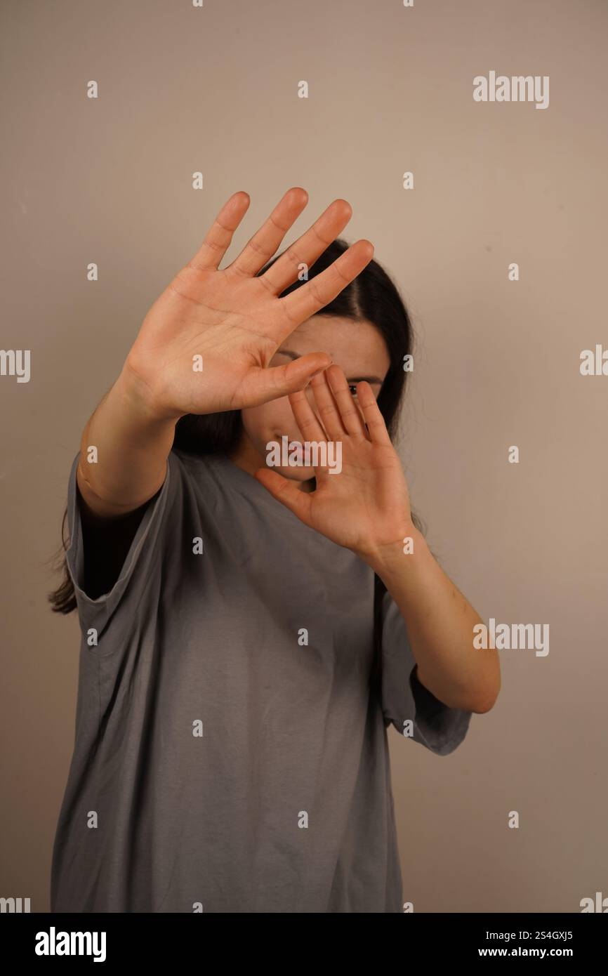 It highlights the theme of domestic violence. A woman holds both hands ...