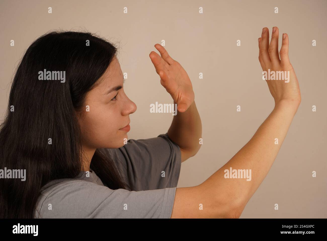 A woman holds both hands in front of her face, a defensive posture ...