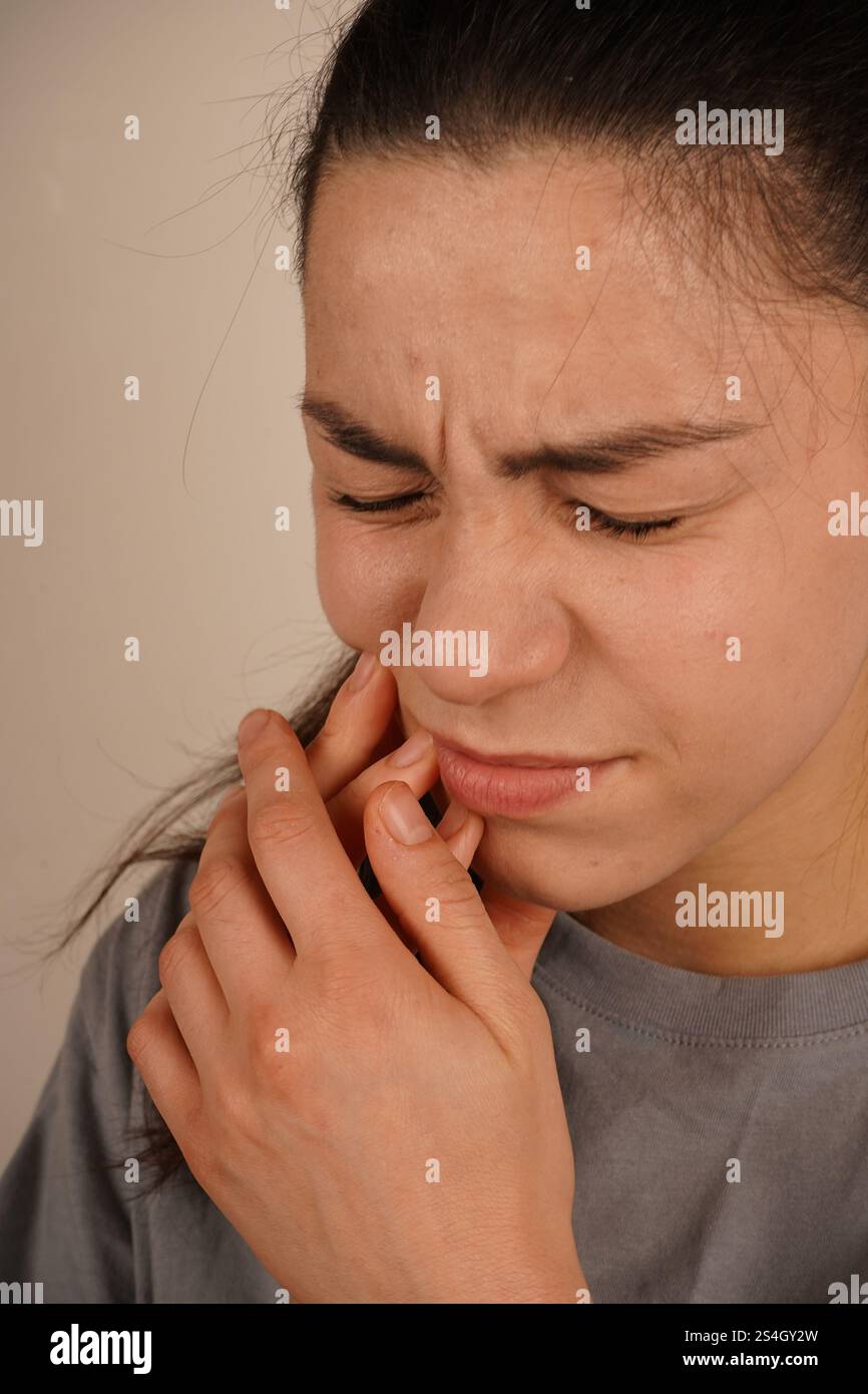 The woman clutches her gum with a pained expression, capturing the ...