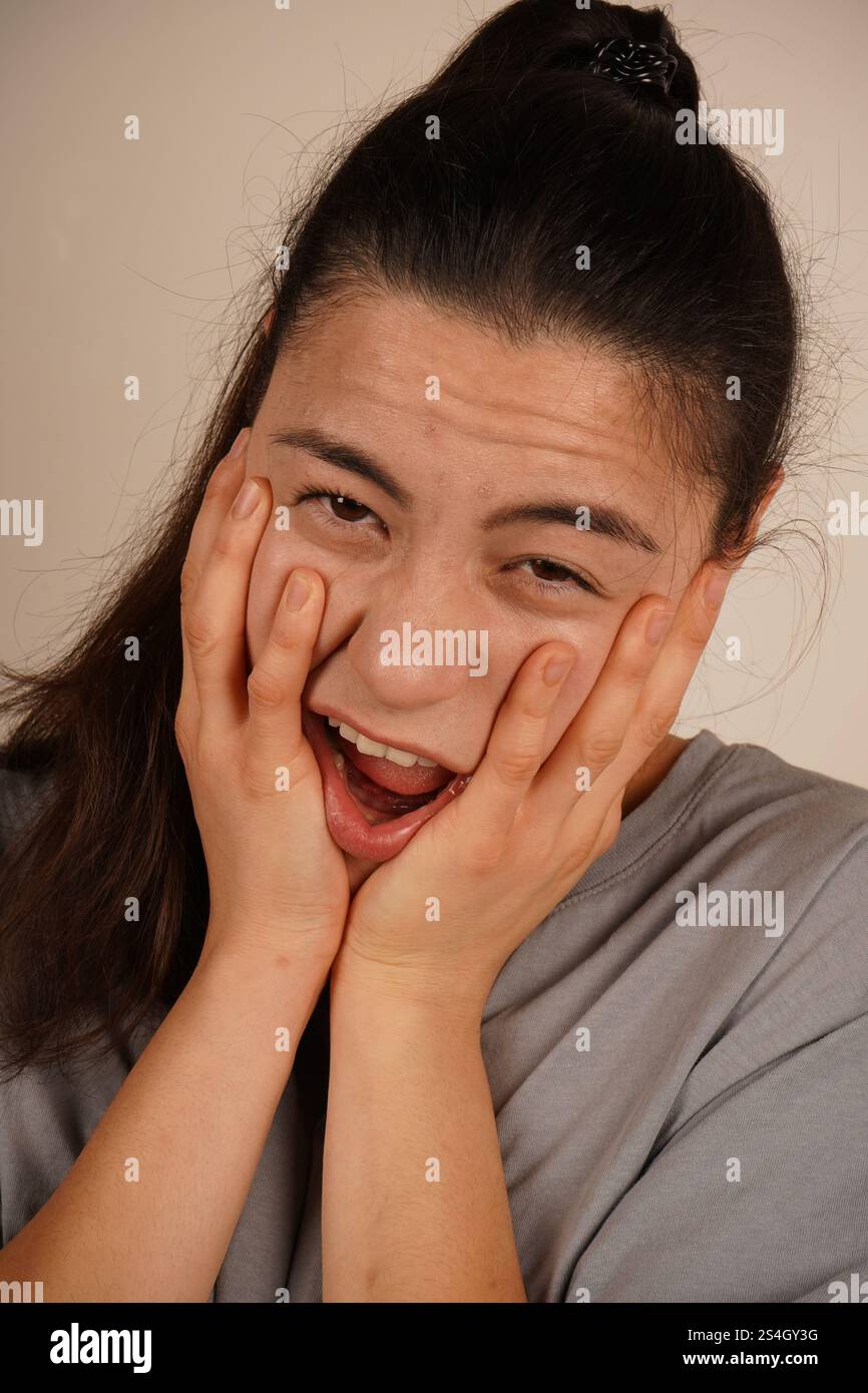 A woman places her hands on her cheeks, her wide-eyed expression ...