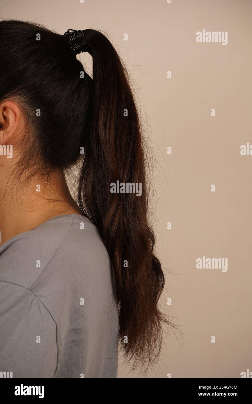 A rear view of a brunette woman with her dark hair styled into a neat ...
