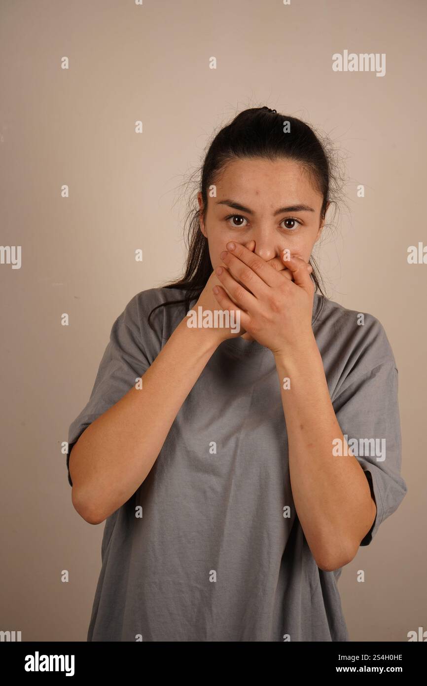 Covering her mouth with her hands, the girl suppresses the urge to ...