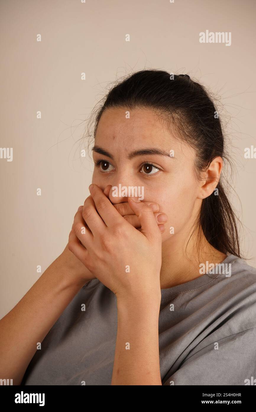 The hands symbolize restraint and control. A woman covers her mouth ...