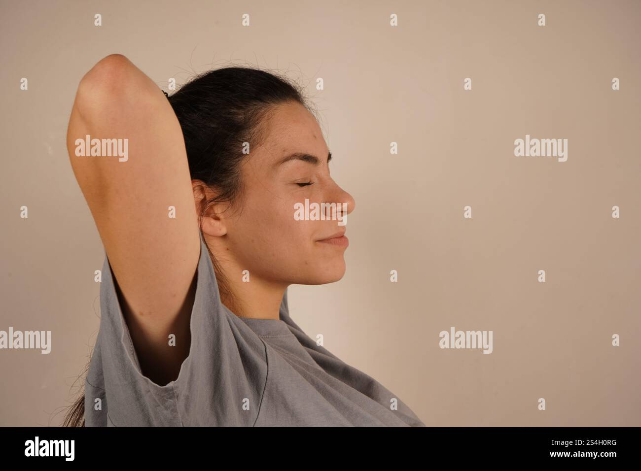 With her hands resting on her head and her elbows bent, her pose ...