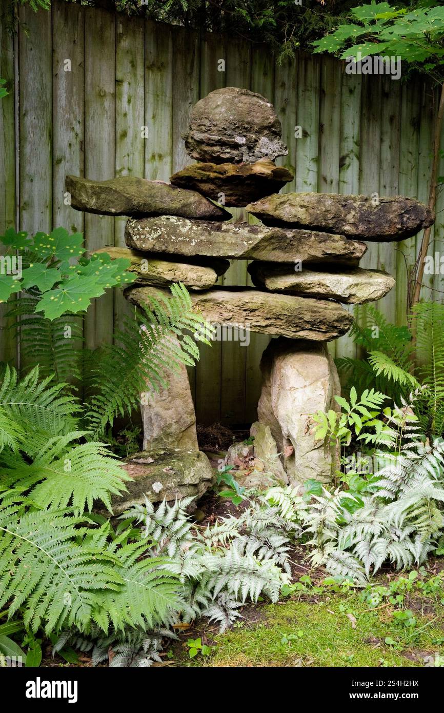 Close-up of Inuit stacked rock sculpture in mixed border in backyard ...