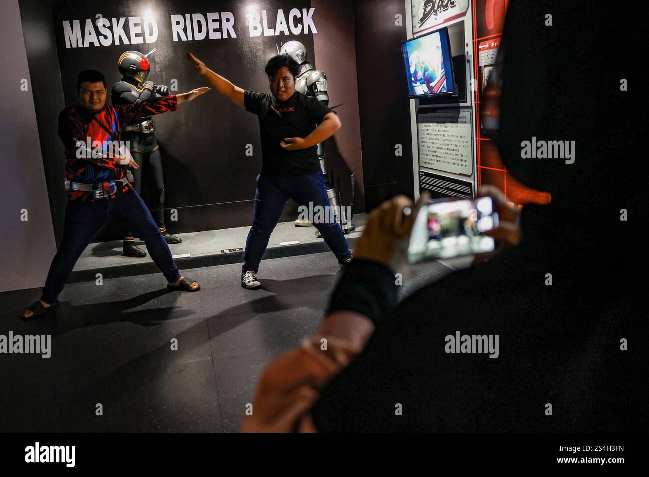 A fan of the Kamen Rider drama series takes a photo with the Kamen ...